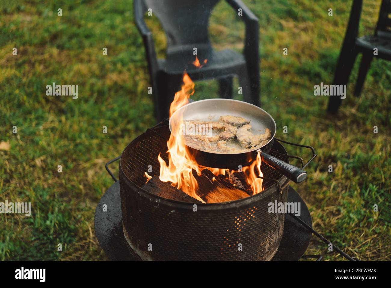 Man cooking fish on fire in nature, camping outdoors Stock Photo - Alamy