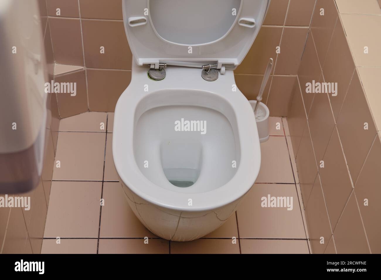 This public bathroom features a sanitary toilet seat and brown tile ...