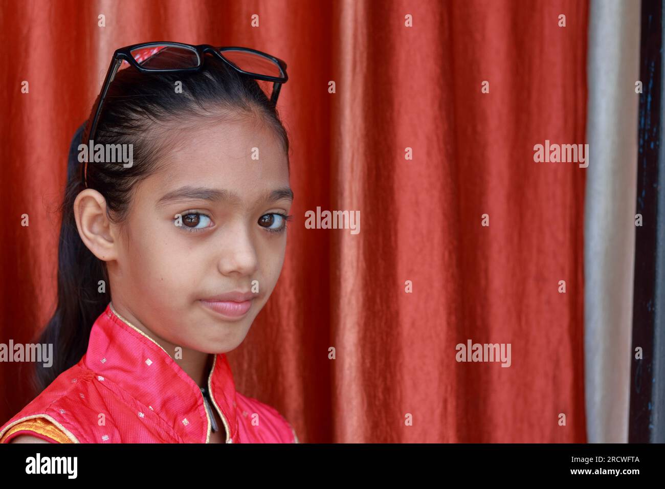 An Indian little pretty girl fiddling with her eye glasses in various ...