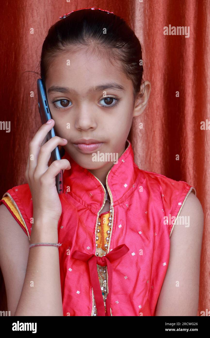An Indian little pretty girl talking on a mobile phone in various poses ...
