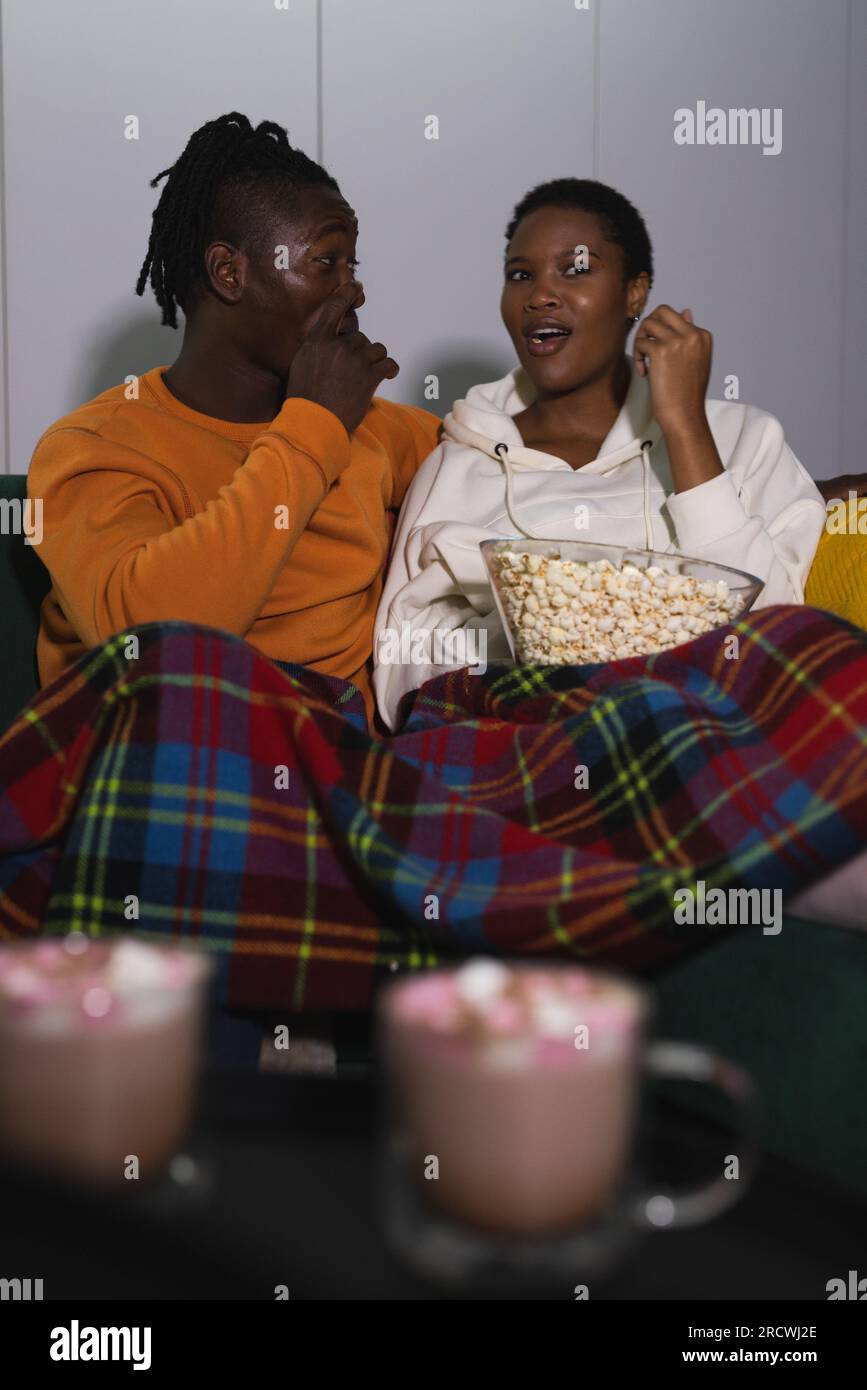 African american couple relaxing at home watching tv and eating popcorn ...
