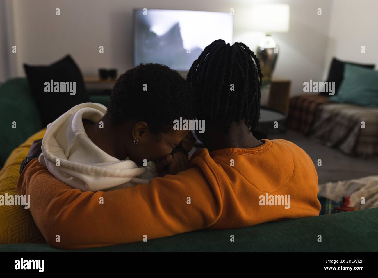 African american couple relaxing at home, scared, hugging, watching ...