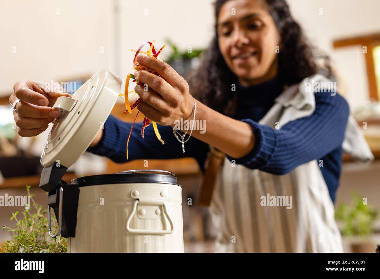 Happy biracial woman wearing apron cleaning waste in kitchen Stock ...