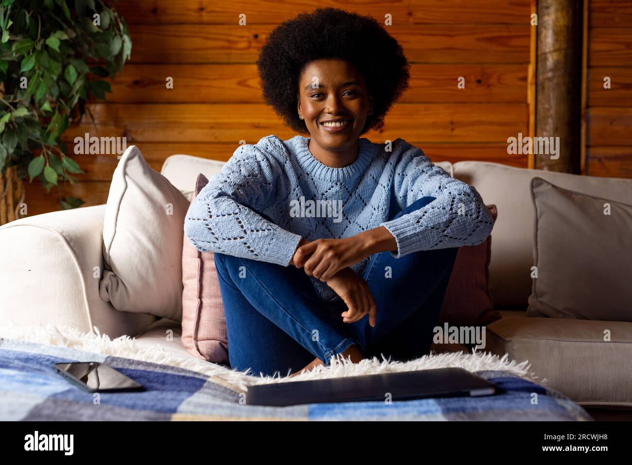 Portrait of happy african american woman sitting on sofa in living room ...