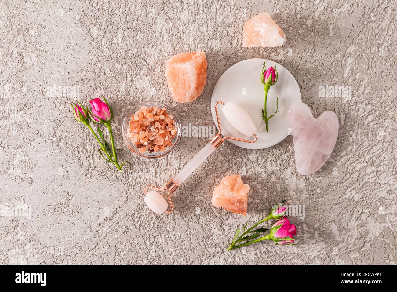 Top view of quartz roller and gua sha on a white round marble stand and ...