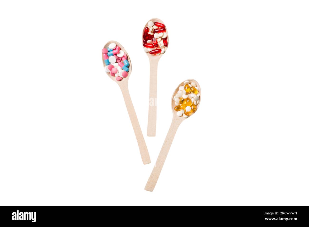 Vitamin capsules in a wooden spoon on a colored background. Pills ...