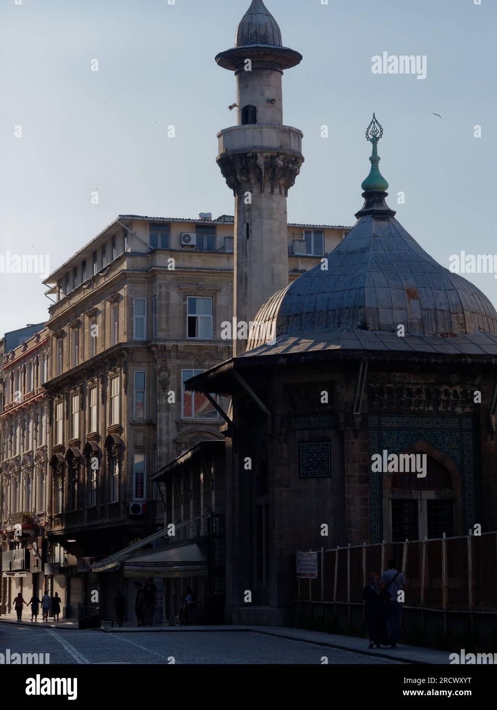 Mosque in shadow in Istanbul as a group of pedestrians walk down the ...
