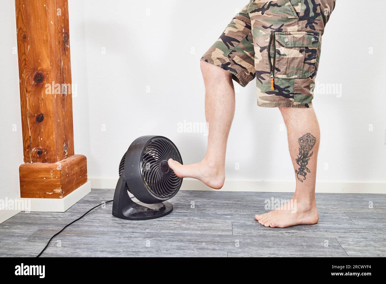 Man cooling feet on fan standing on floor Stock Photo - Alamy