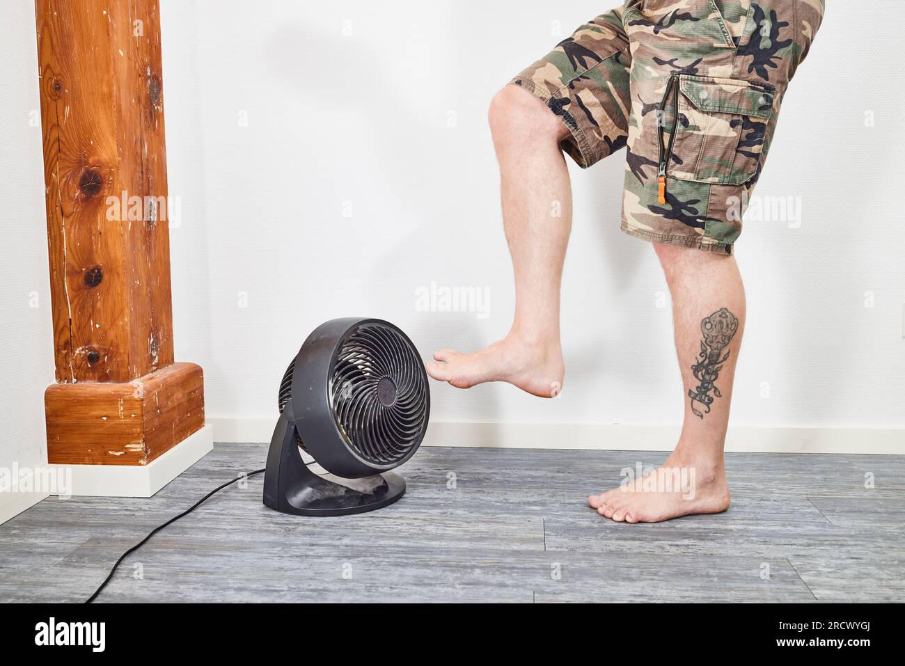 Man cooling feet on fan standing on floor Stock Photo - Alamy