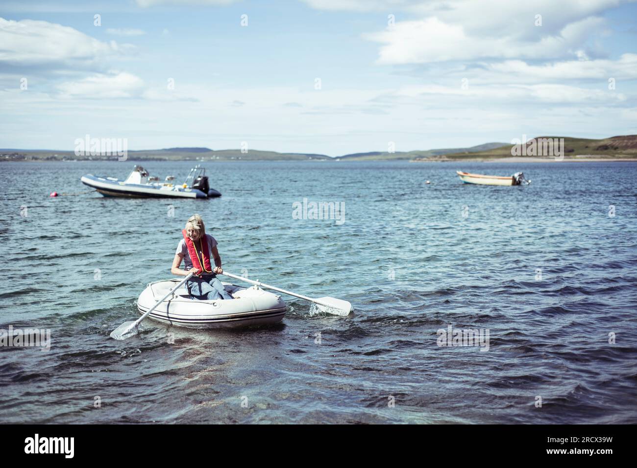 Strong retired woman rows boat in sea Stock Photo - Alamy