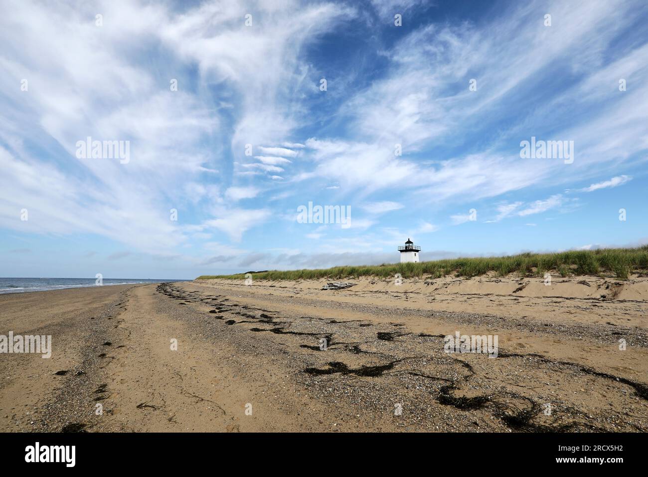 A beautiful blue sky and long stretch of sand leads to a lighthouse ...