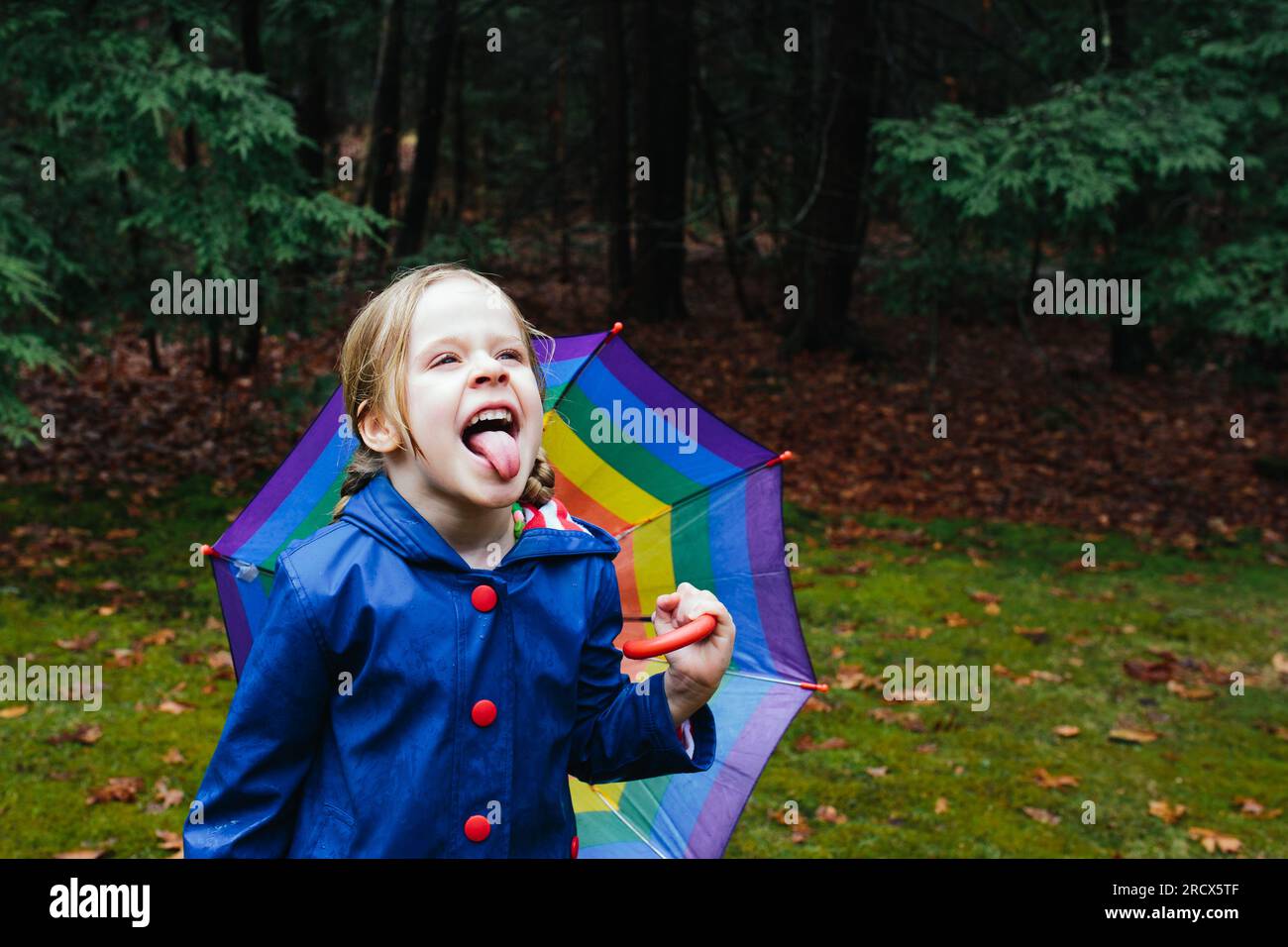 Young girl in blue rain jacket catching raindrops on her tongue Stock ...