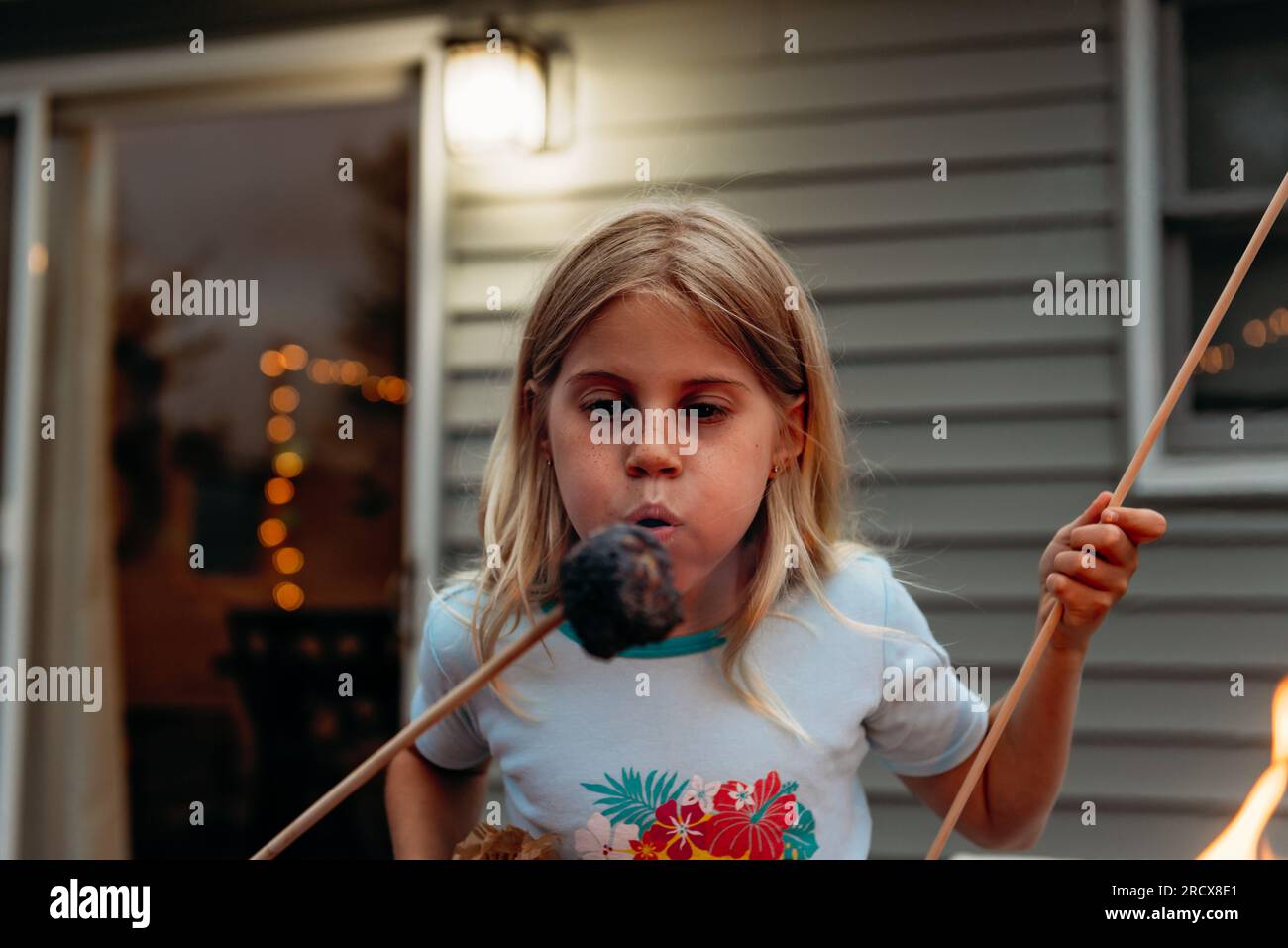 Girl blowing out marshmallow while making s'mores Stock Photo - Alamy