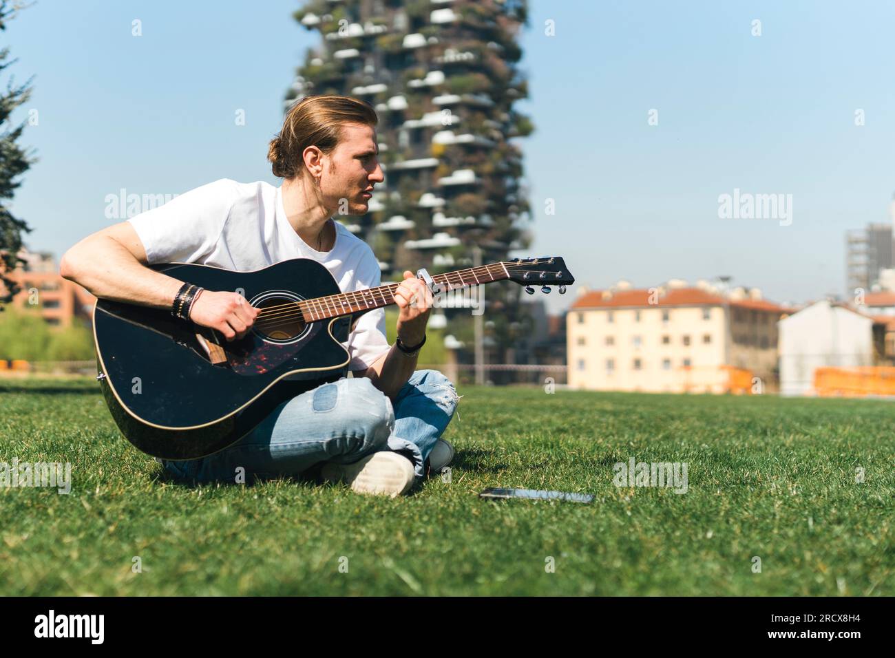 Young white singer play the guitar in a garden during a sunny day Stock ...