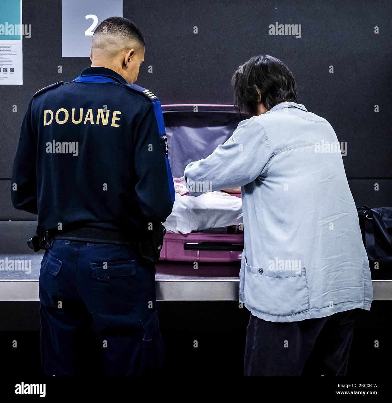 SCHIPHOL - A customs officer inspects a suitcase at Schiphol Airport ...