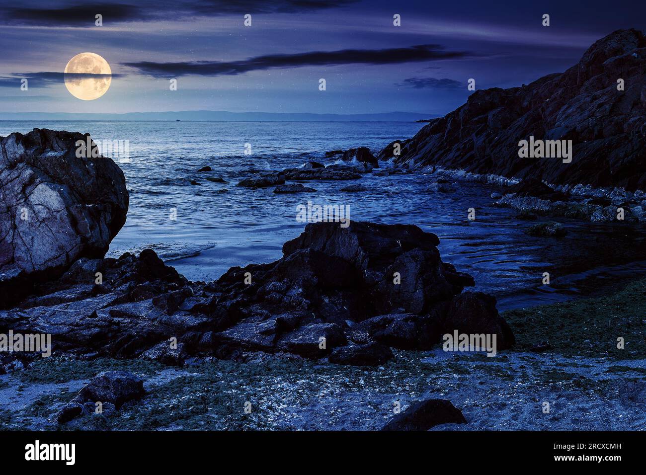 number of stones and rock on the sandy sea coast at night. seaweed lie ...