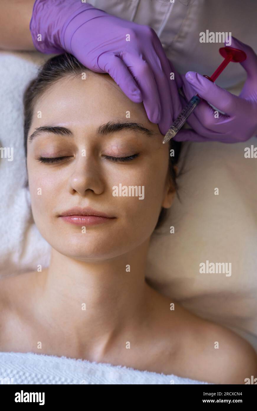 Cosmetologist's hands making the rejuvenating facial injections ...