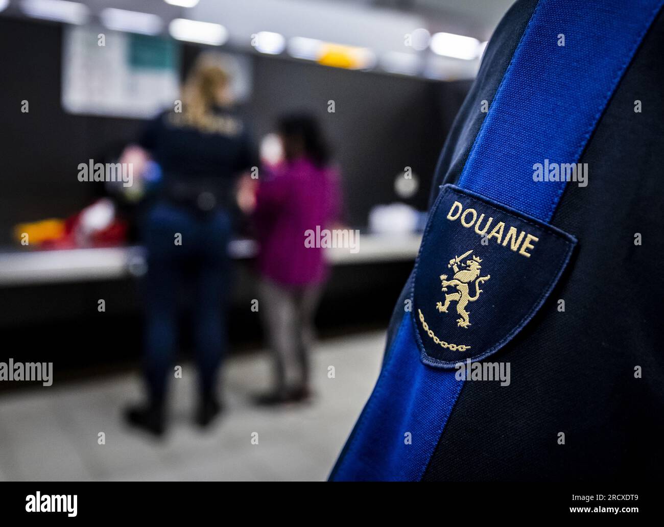 SCHIPHOL - A customs officer inspects a suitcase at Schiphol Airport ...