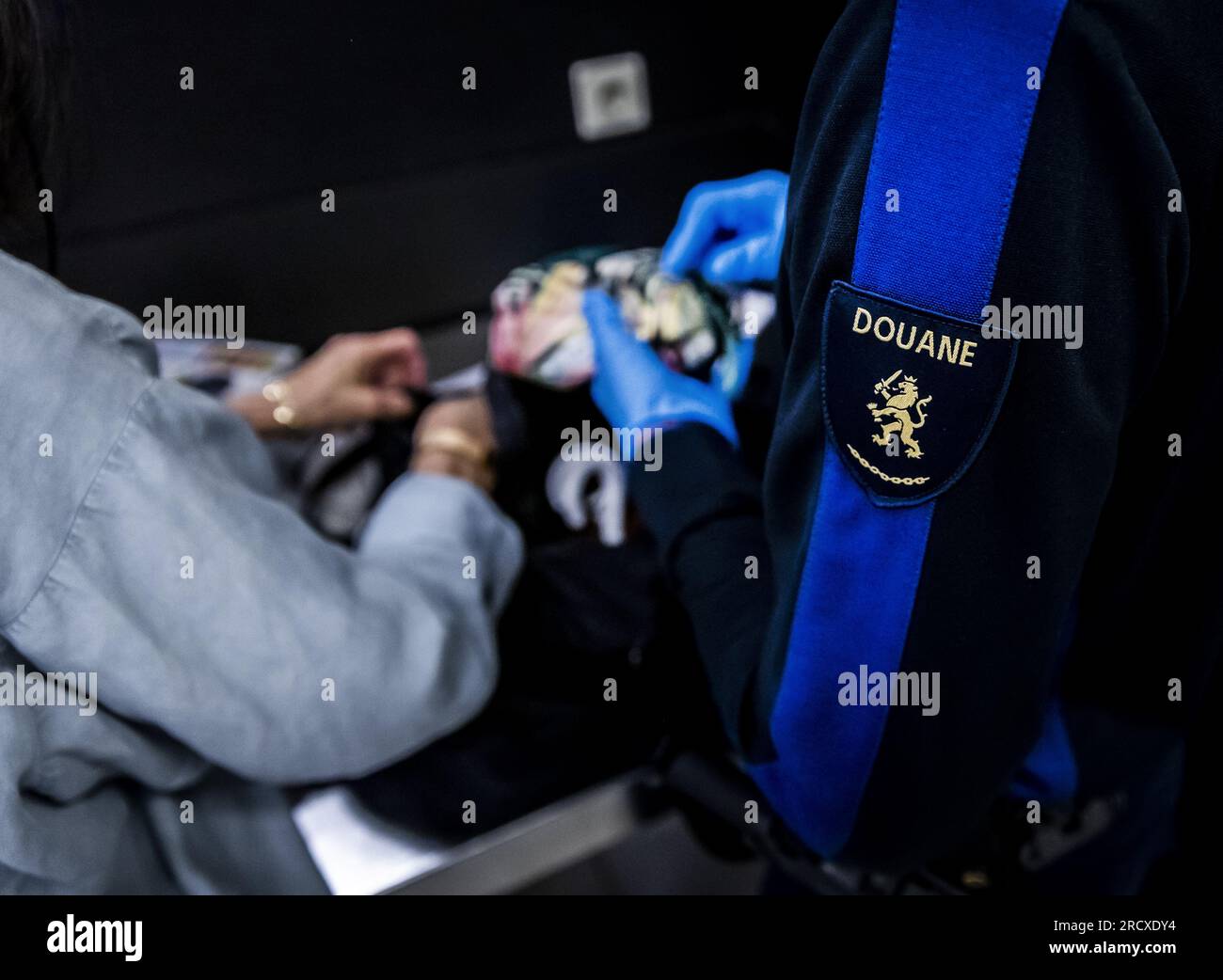 SCHIPHOL - A customs officer inspects a suitcase at Schiphol Airport ...