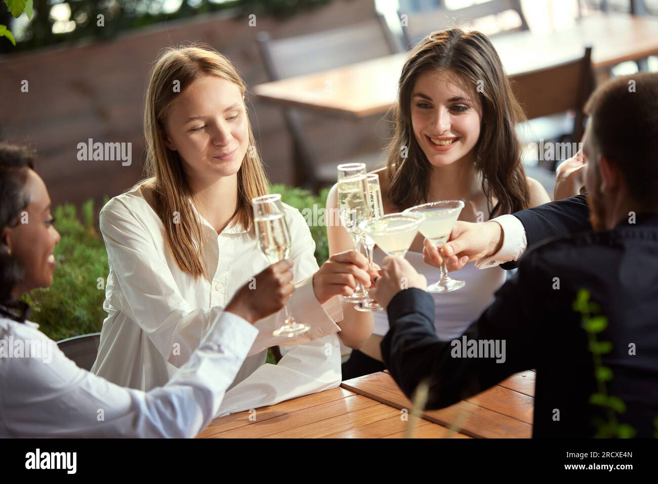 Cheerful young people, colleagues meeting in restaurant after work ...