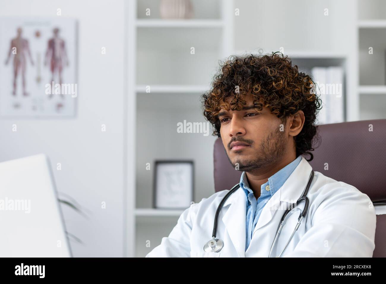 Close-up photo. Portrait of a young Indian male doctor sitting in an ...