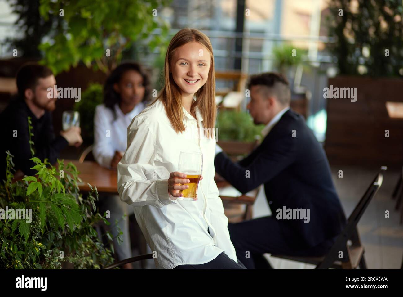 Focus on smiling young woman employee standing with beer. Blurred ...