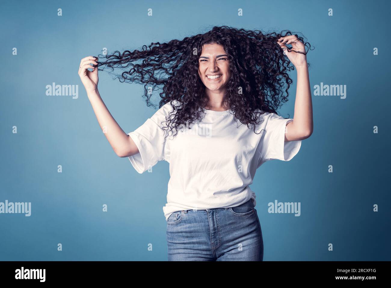 Shot of happy confident curly woman with toothy smile, wears casual ...