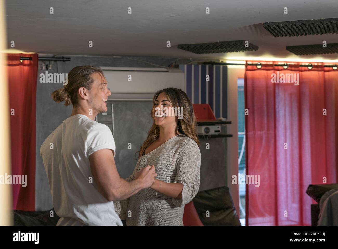 Inside house couple shooting dancing in living room having fun, smiling ...