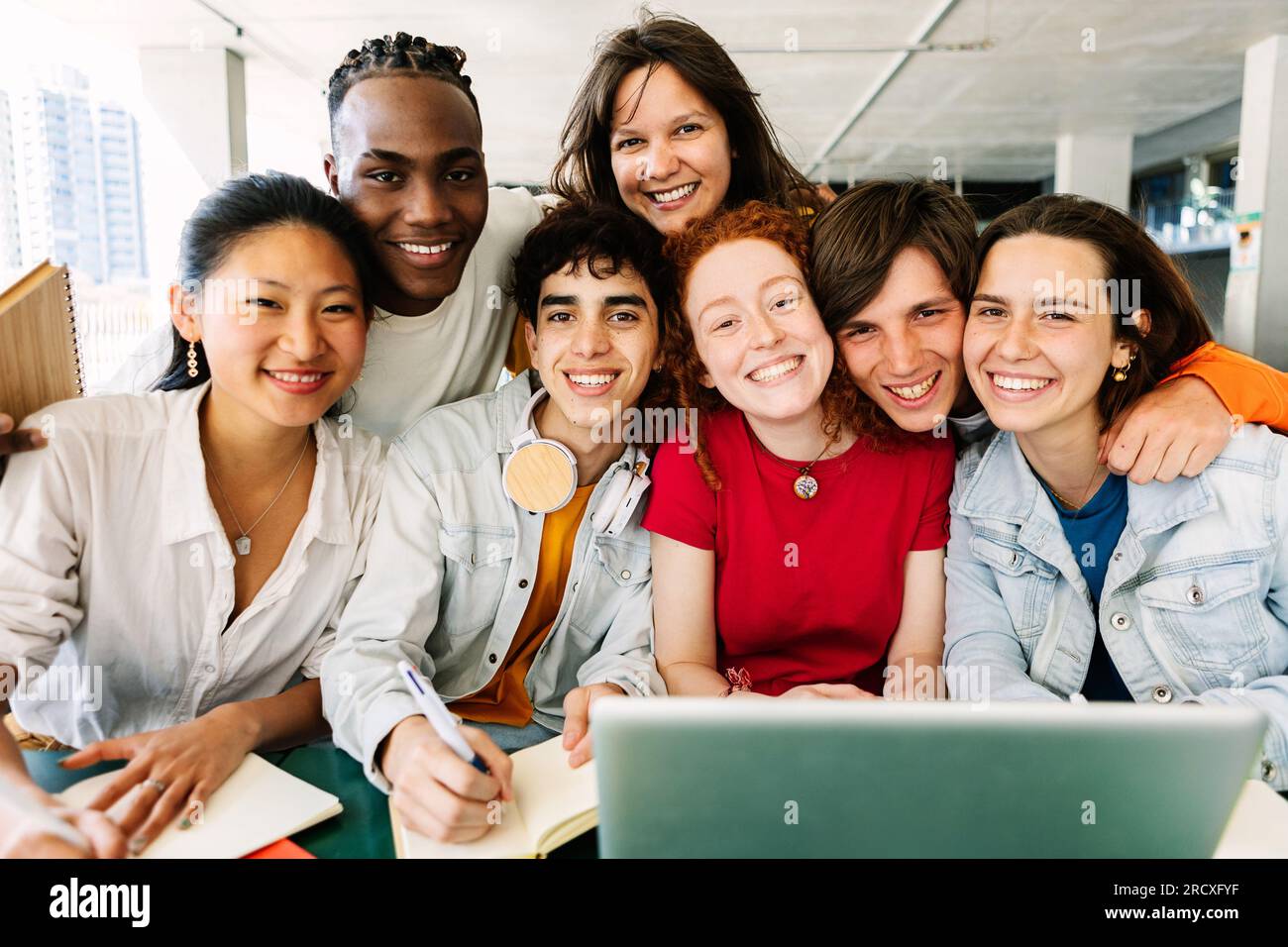 Group portrait of multiracial students with laptop and books smiling at ...