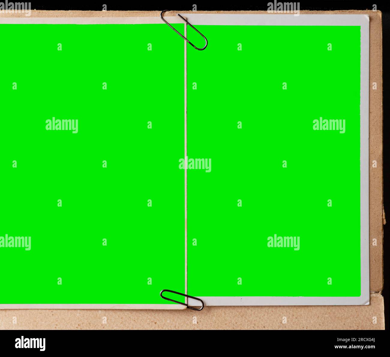 A vintage book page with blank photo frames attached with paper clips ...