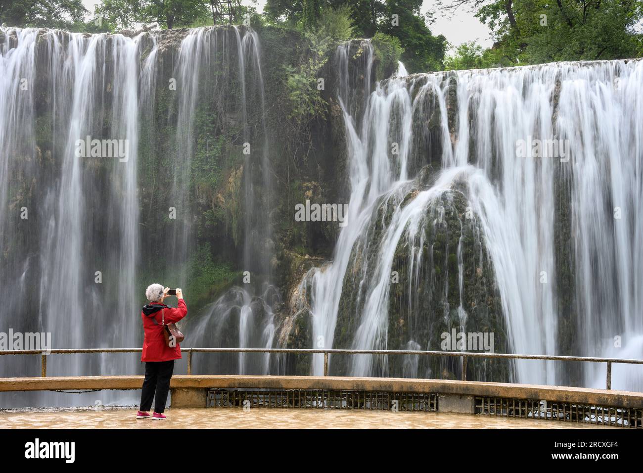 A tourist photographs the Pliva Waterfall at Jajce in central Bosnia ...