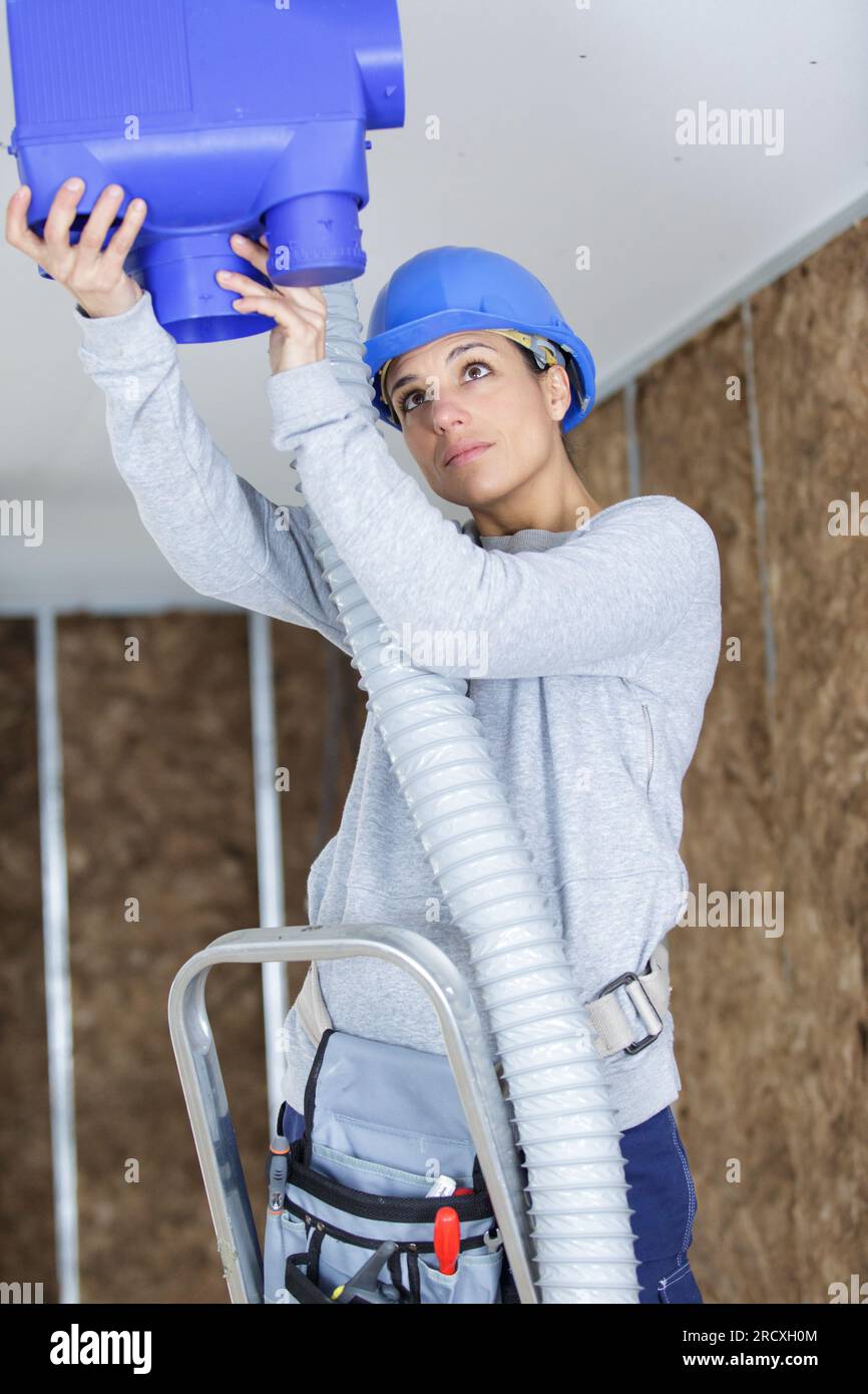 female worker installing plastic ventilation unit Stock Photo - Alamy