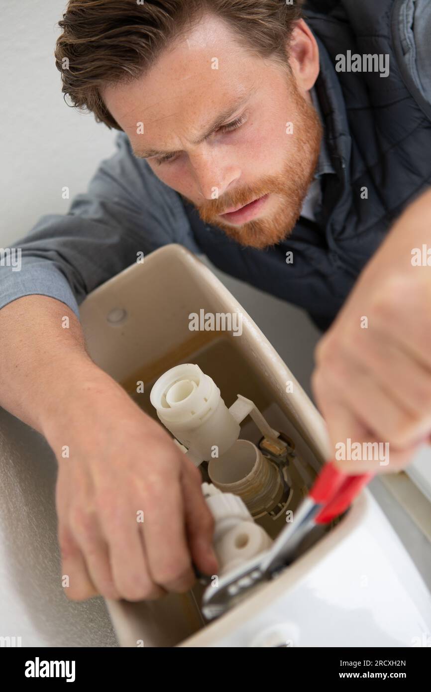 plumber repairing toilet cistern at water closet Stock Photo - Alamy