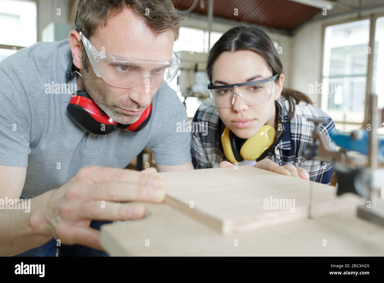 carpenter training female apprentice to use mechanized saw Stock Photo ...