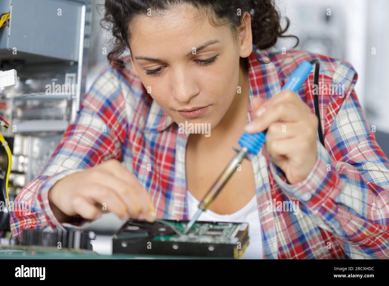 young female electronic engineer soldering computer motherboard in ...