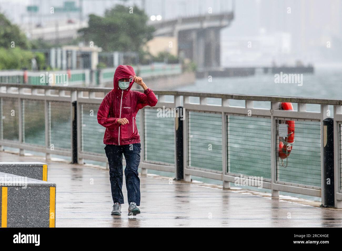 Hong Kong, China. 17th July, 2023. A woman tries to keep out the wind ...