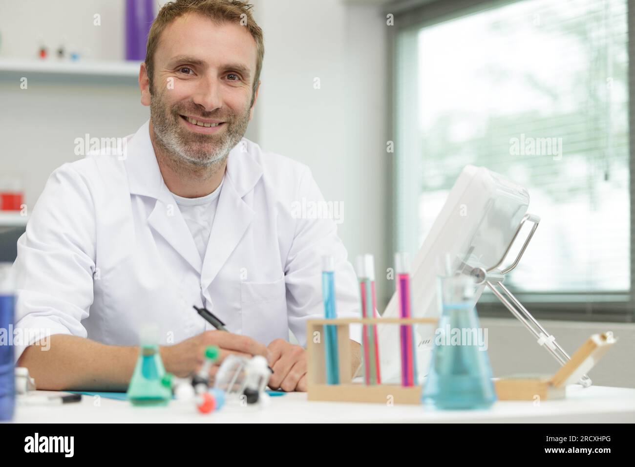 happy male researcher holding flask with blue liquid Stock Photo - Alamy