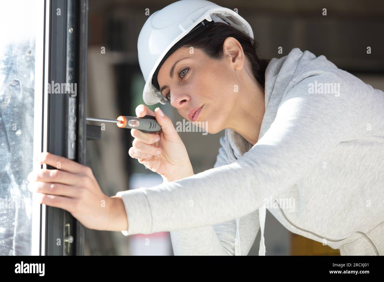 female builder tightening screw on window with screwdriver Stock Photo ...
