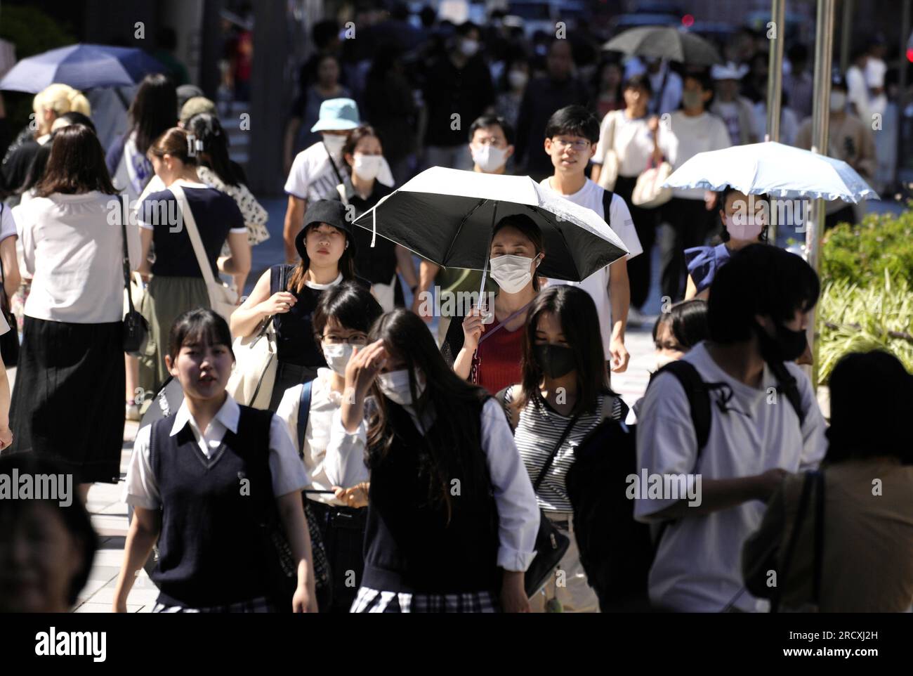 People walk with parasols on a sweltering hot day in the central Japan ...