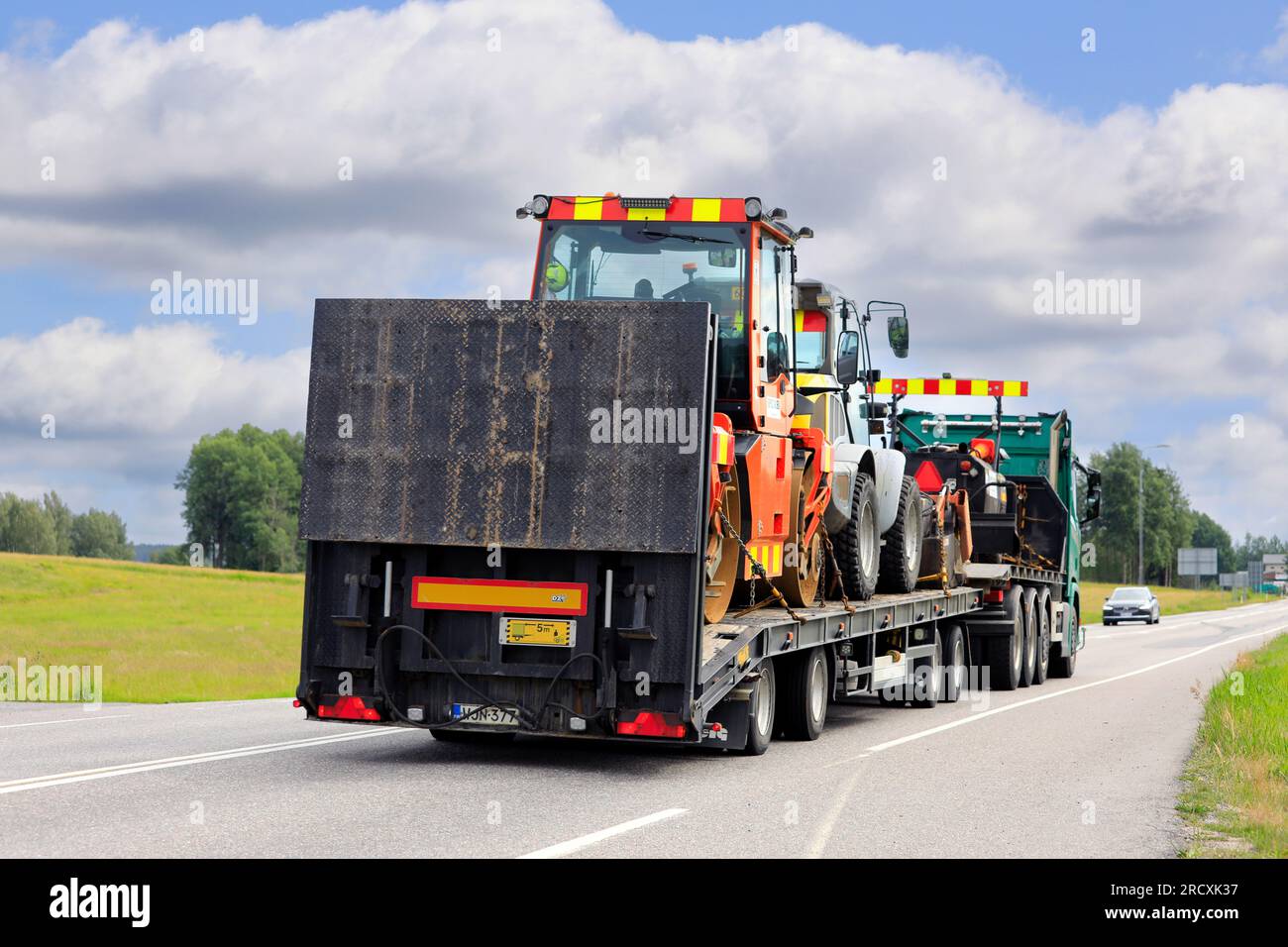 Green Scania truck transports roadworks asphalting machinery on flat ...