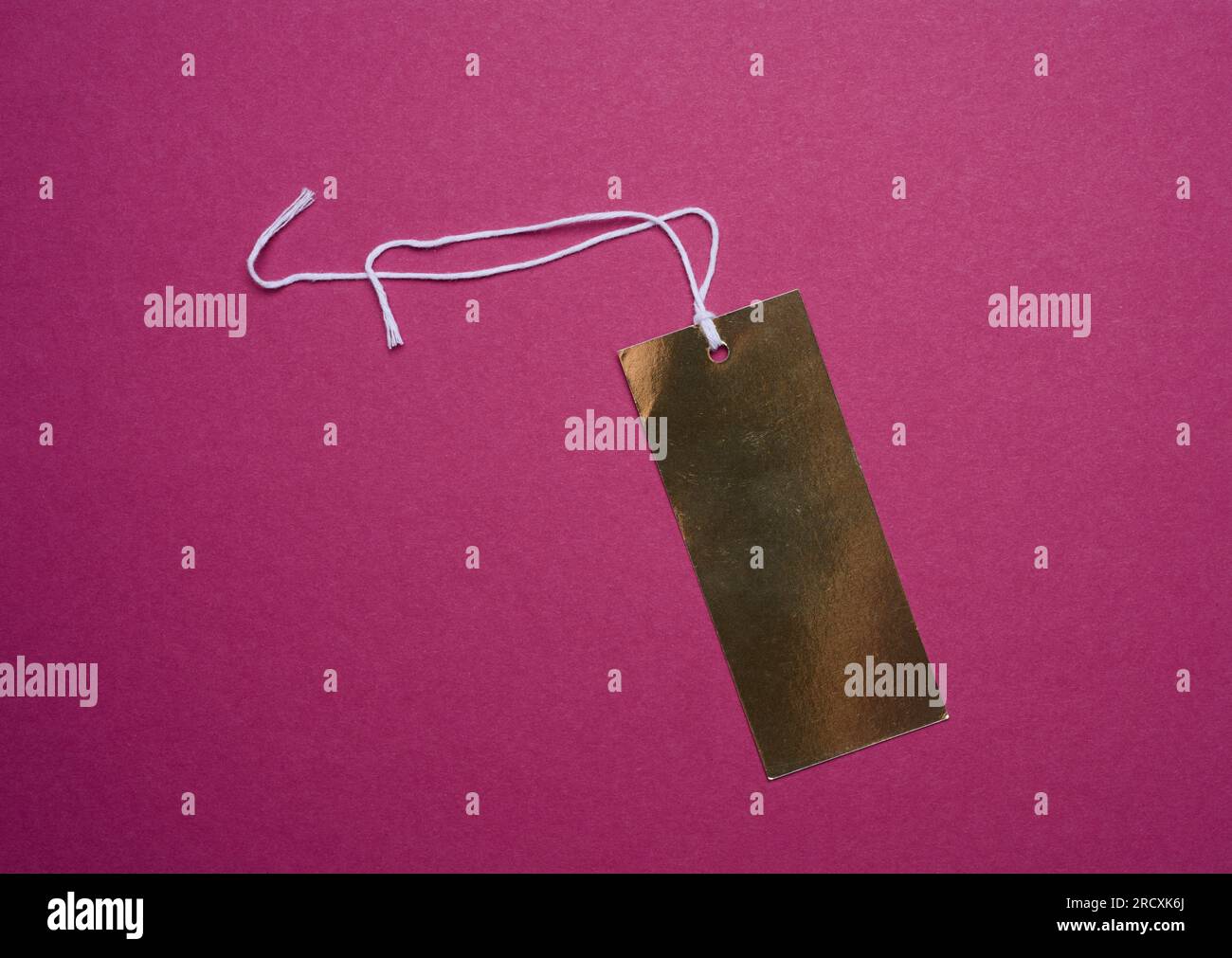 Golden price tag with a white string for clothing and merchandise on a ...