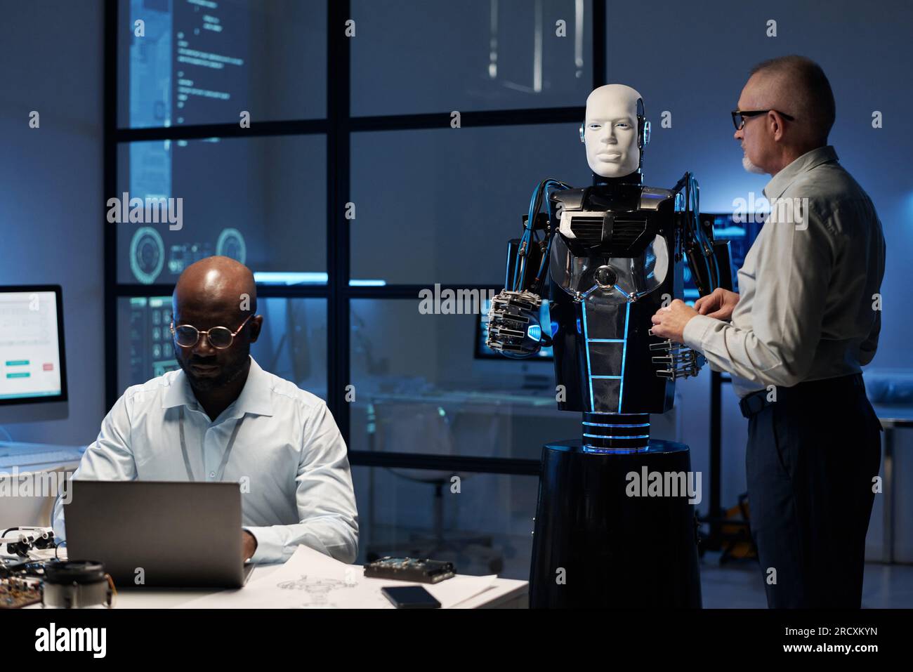 Two multiethnic engineers programming robot in the lab using computers ...