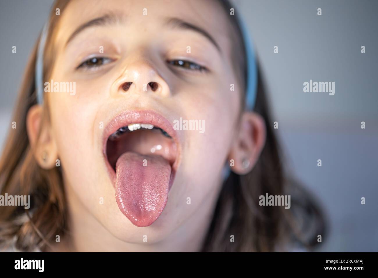 A child girl open her mouth and show her tounge Stock Photo - Alamy