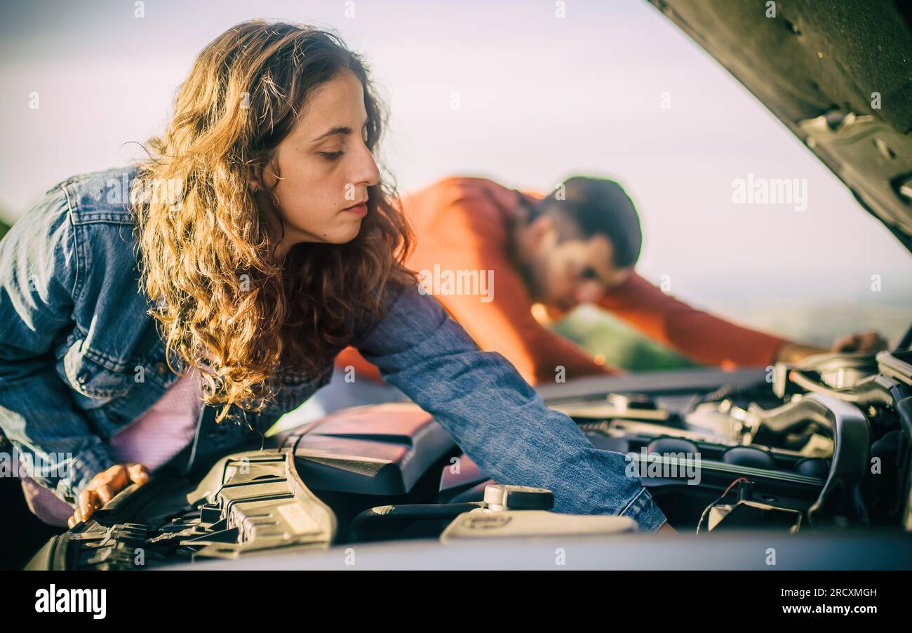 A young couple had a car breakdown on the road. They stand very upset ...