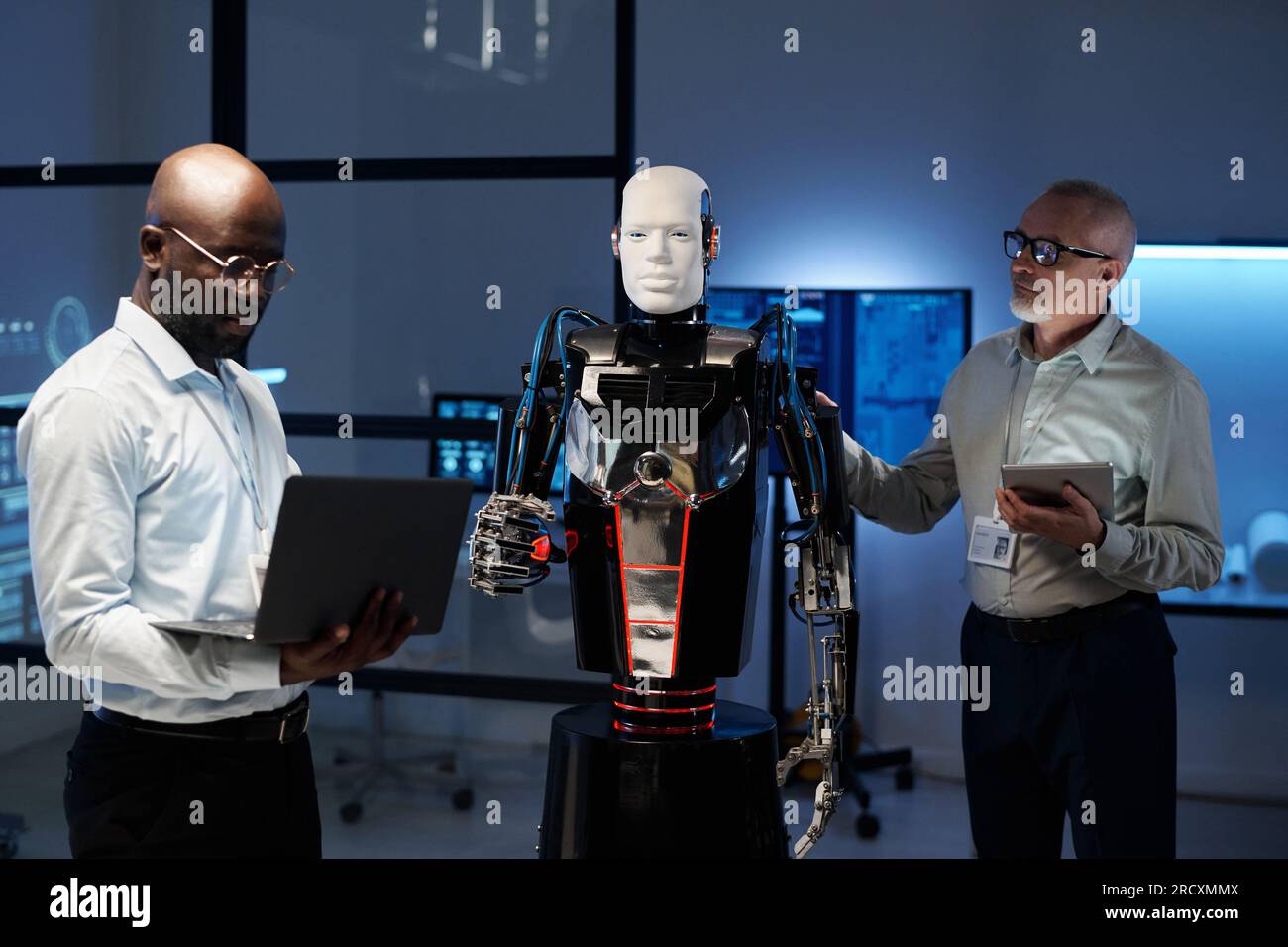 Engineers using gadgets to connect robot during their teamwork in the ...