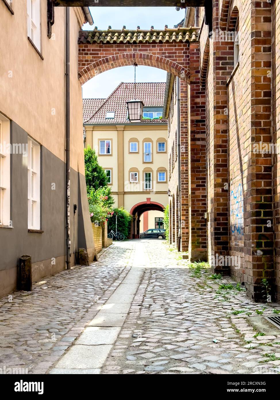 Narrow European street with brick buildings and paving stones Stock ...