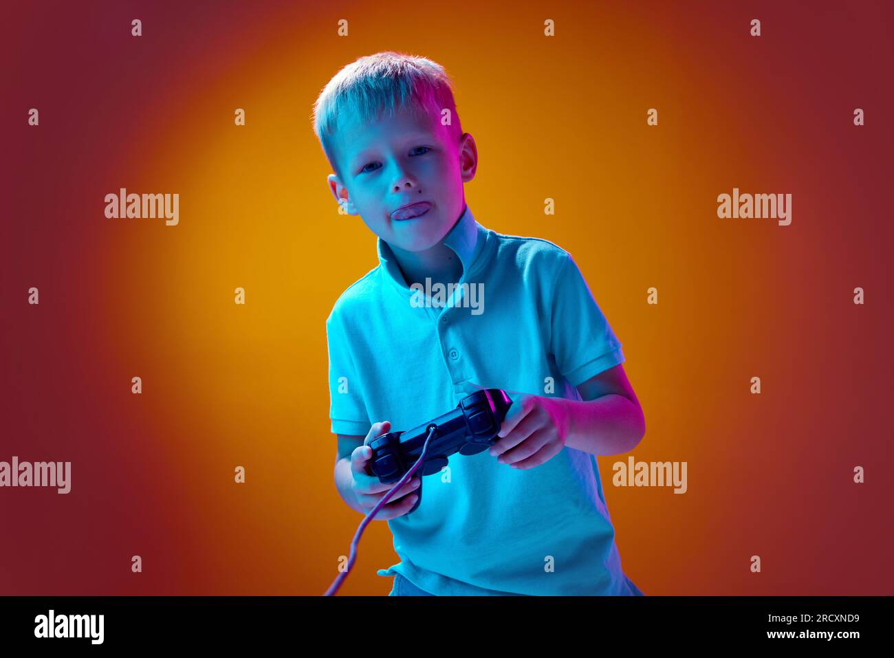 Playful little boy, child playing console against gradient yellow ...