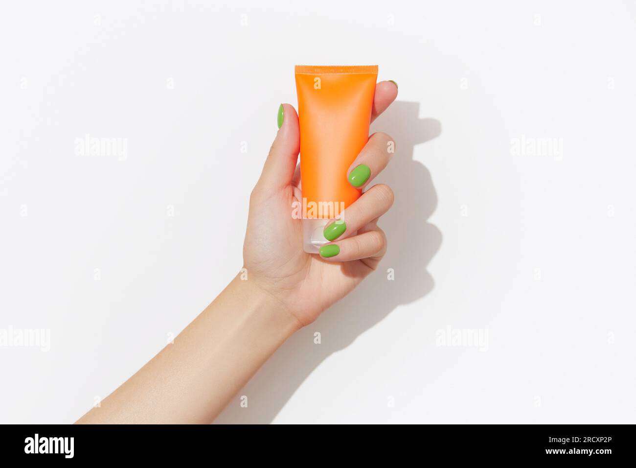 Womans hand holding sunscreen tube on white background. Self care ...