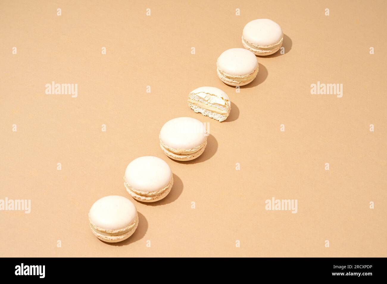 A still life image featuring six white macarons, arranged in a stack on ...