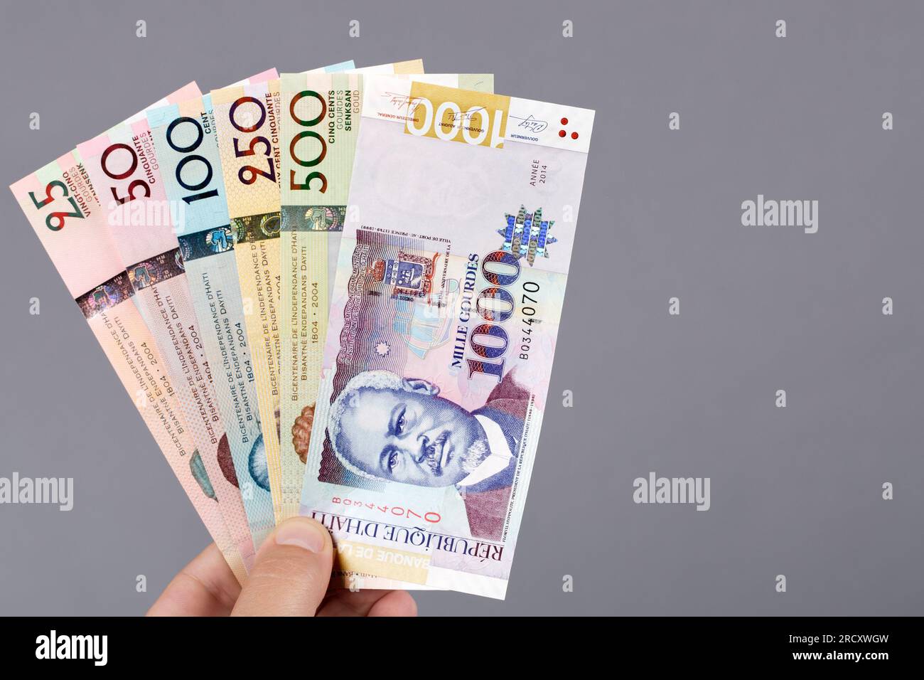 Haitian money - gourde in the hand on a gray background Stock Photo - Alamy